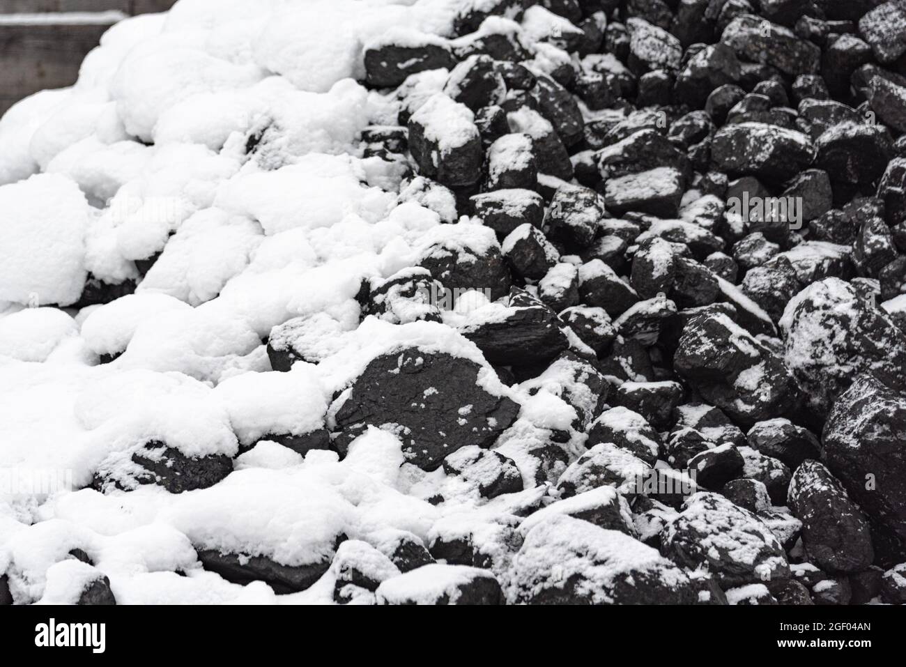 Coal covered with snow. Winter weather, fuel for heating homes. Storage ...