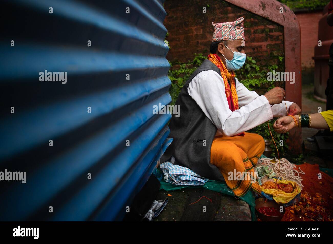 A Hindu priest ties a sacred thread on a hand of a kid during the Janai ...