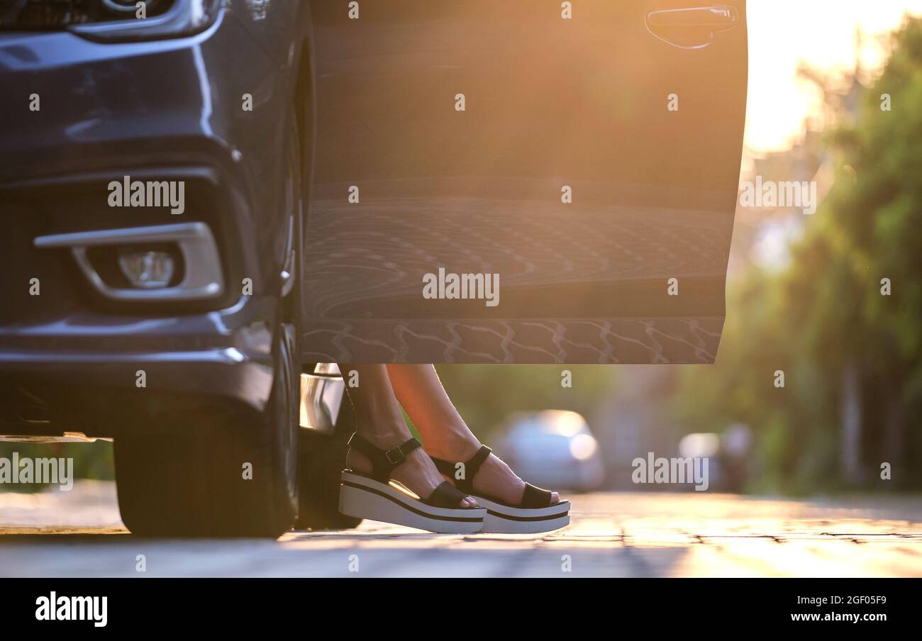 Closeup of woman driver legs getting out of her car. Transportation and ...