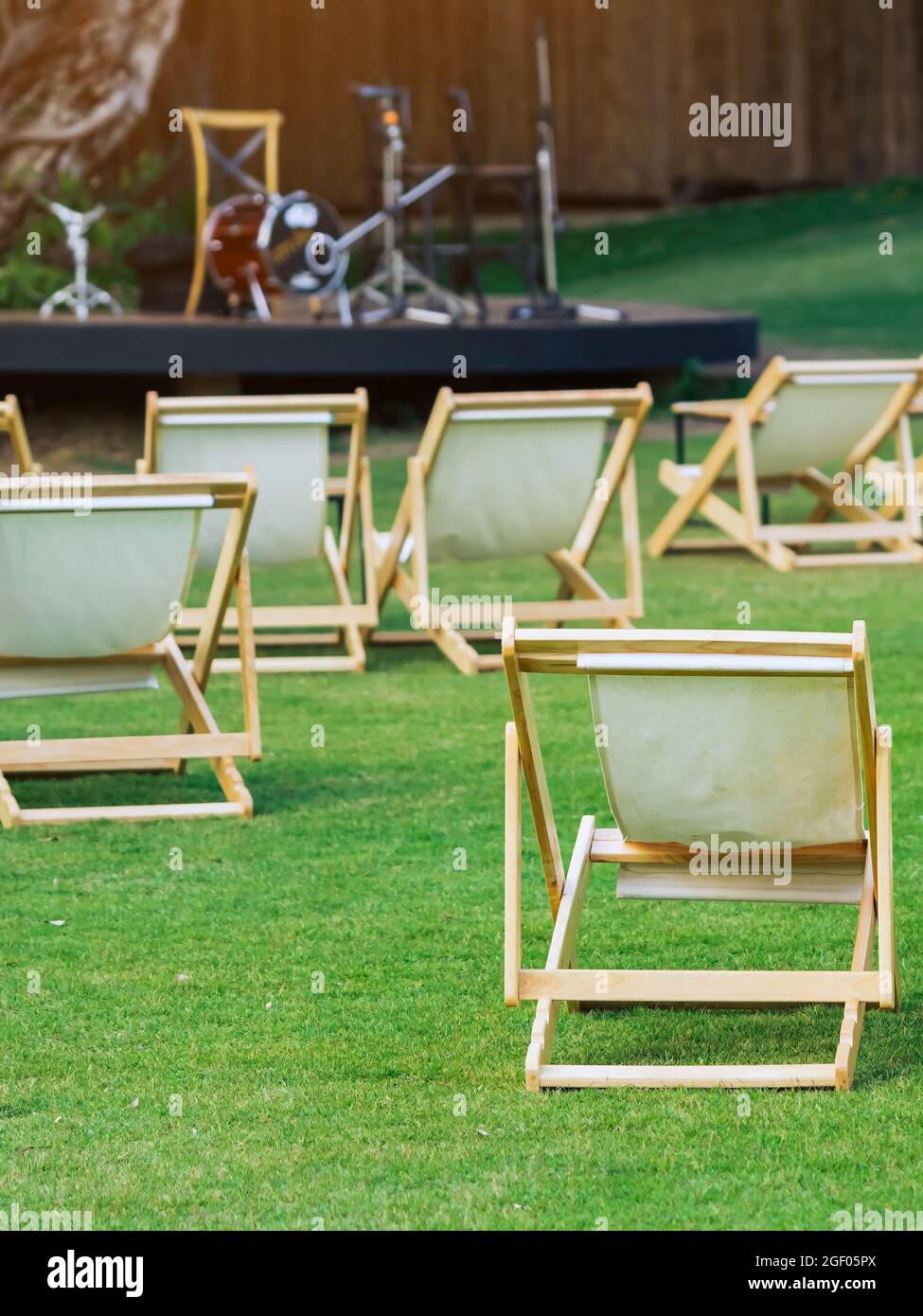 Many empty white deck chairs with tables in lawn is surrounded by shady ...