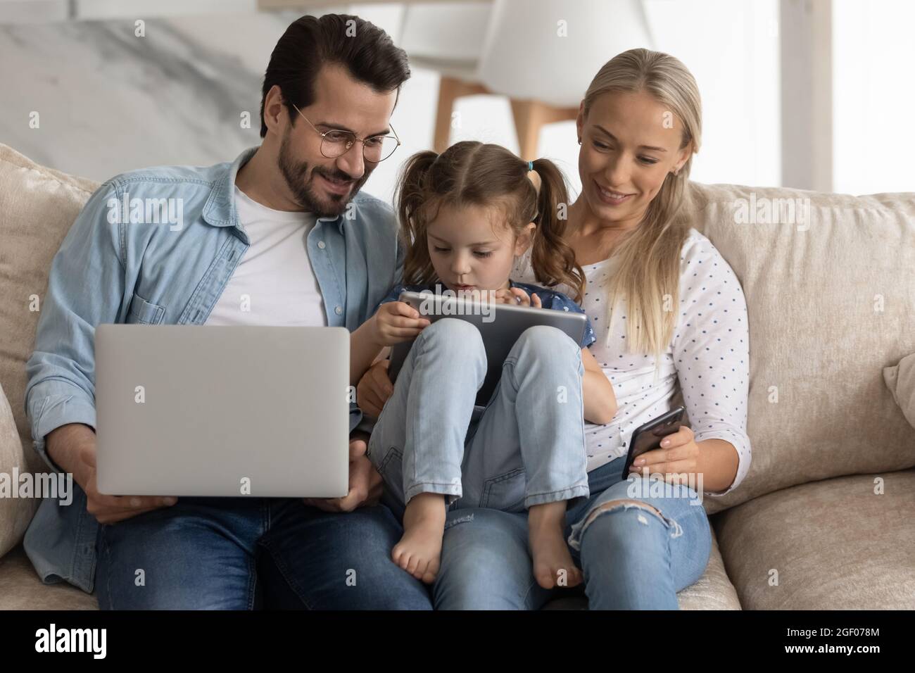 Happy family couple with little kid engaged in gadgets using Stock ...