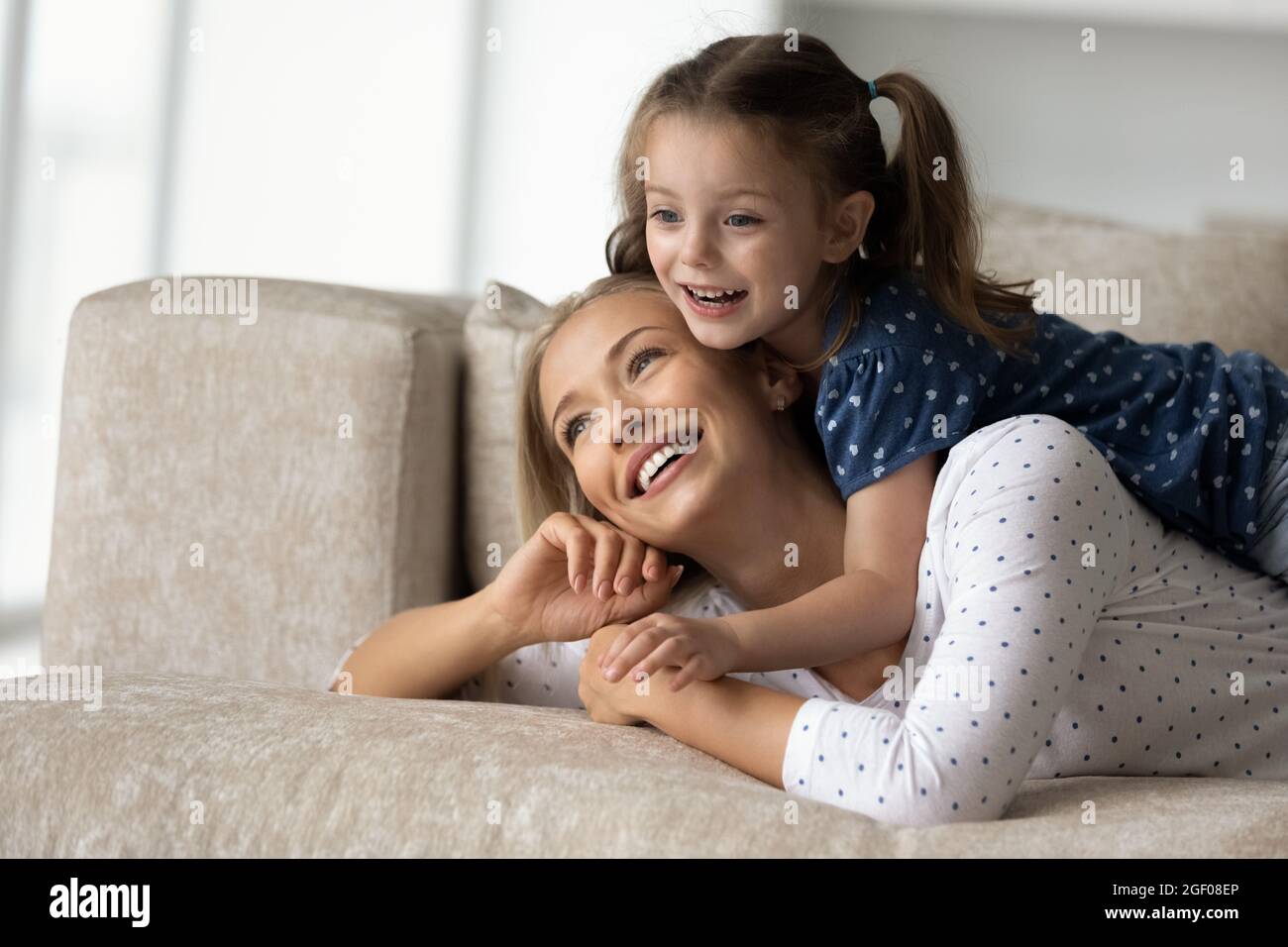 Laughing mom and daughter kid resting on couch at home Stock Photo - Alamy
