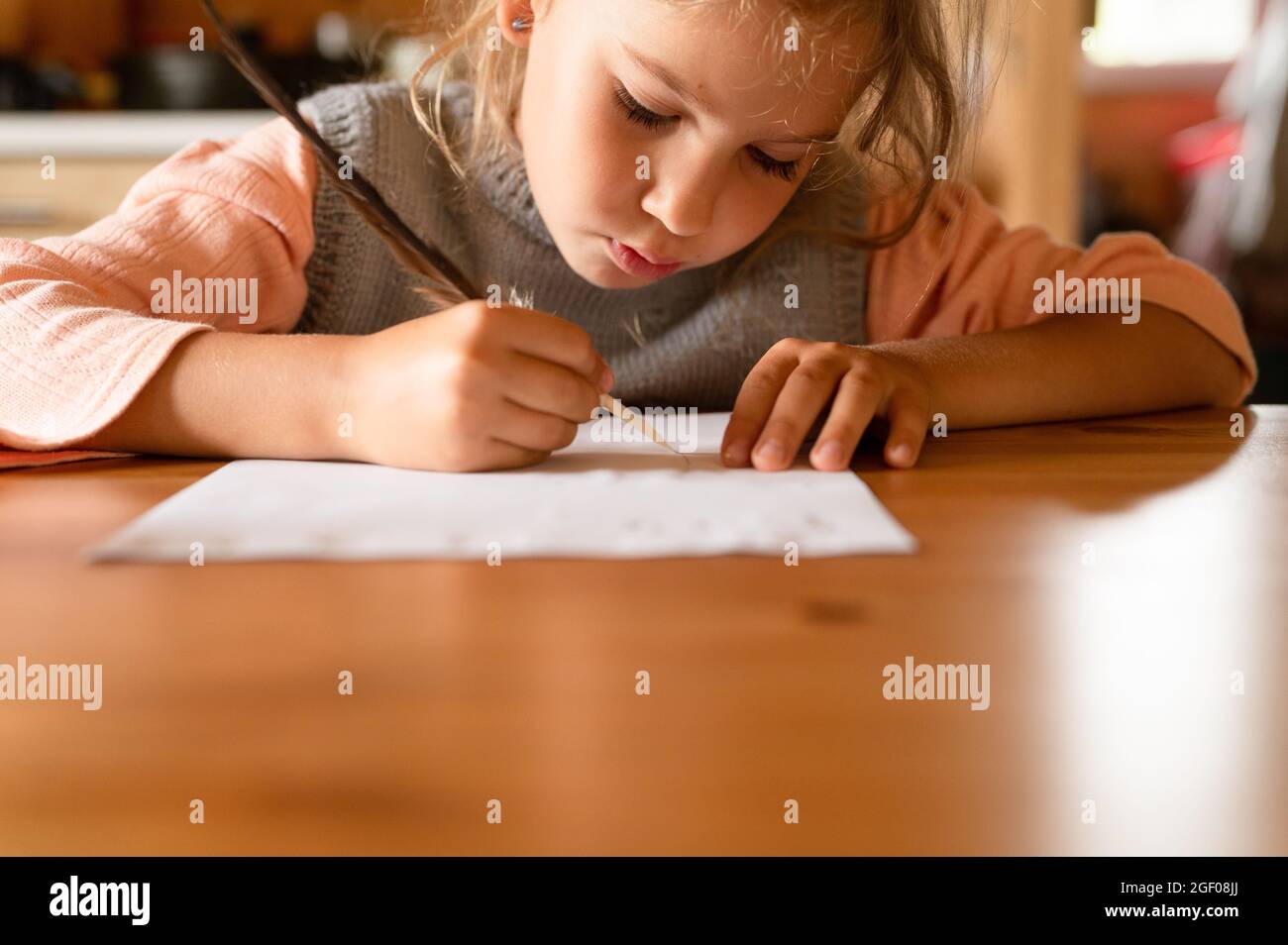 little seven year old kid girl draws a disappearing drawing on a paper ...
