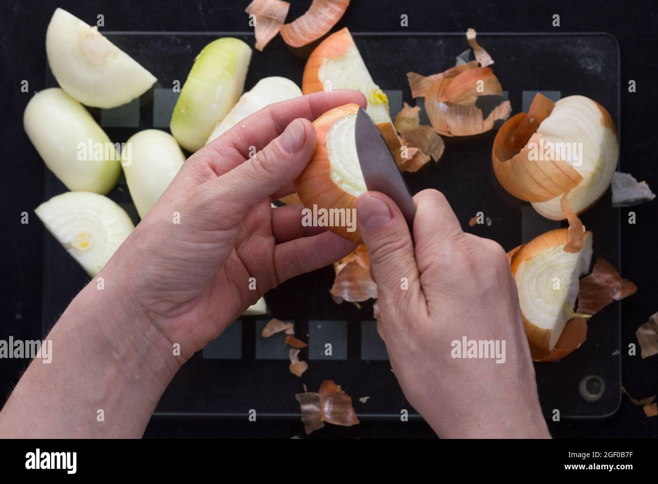 Top view of woman hands peeling off with knife cutted in half unpeeled ...