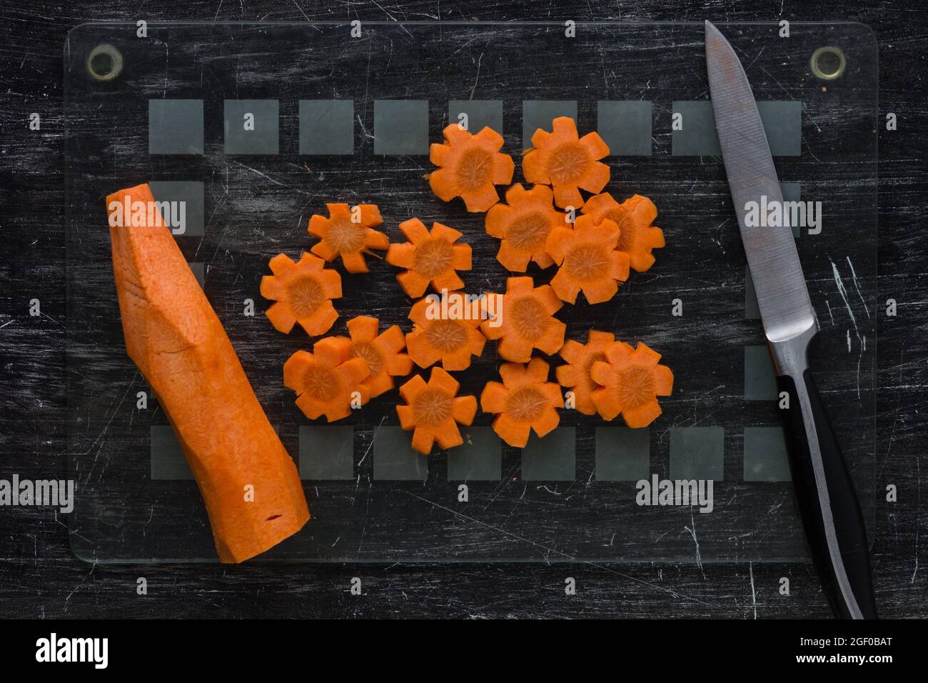 Top view of cutting on round decorative slices raw carrot on black ...