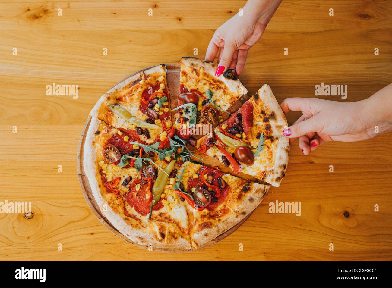 Top view of females picking up pizza slices from the table Stock Photo ...
