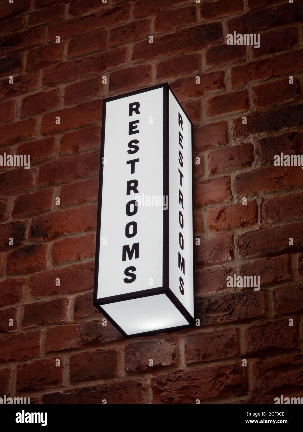 A vertical shot of a rectangular "RESTROOMS" sign with white led lights ...