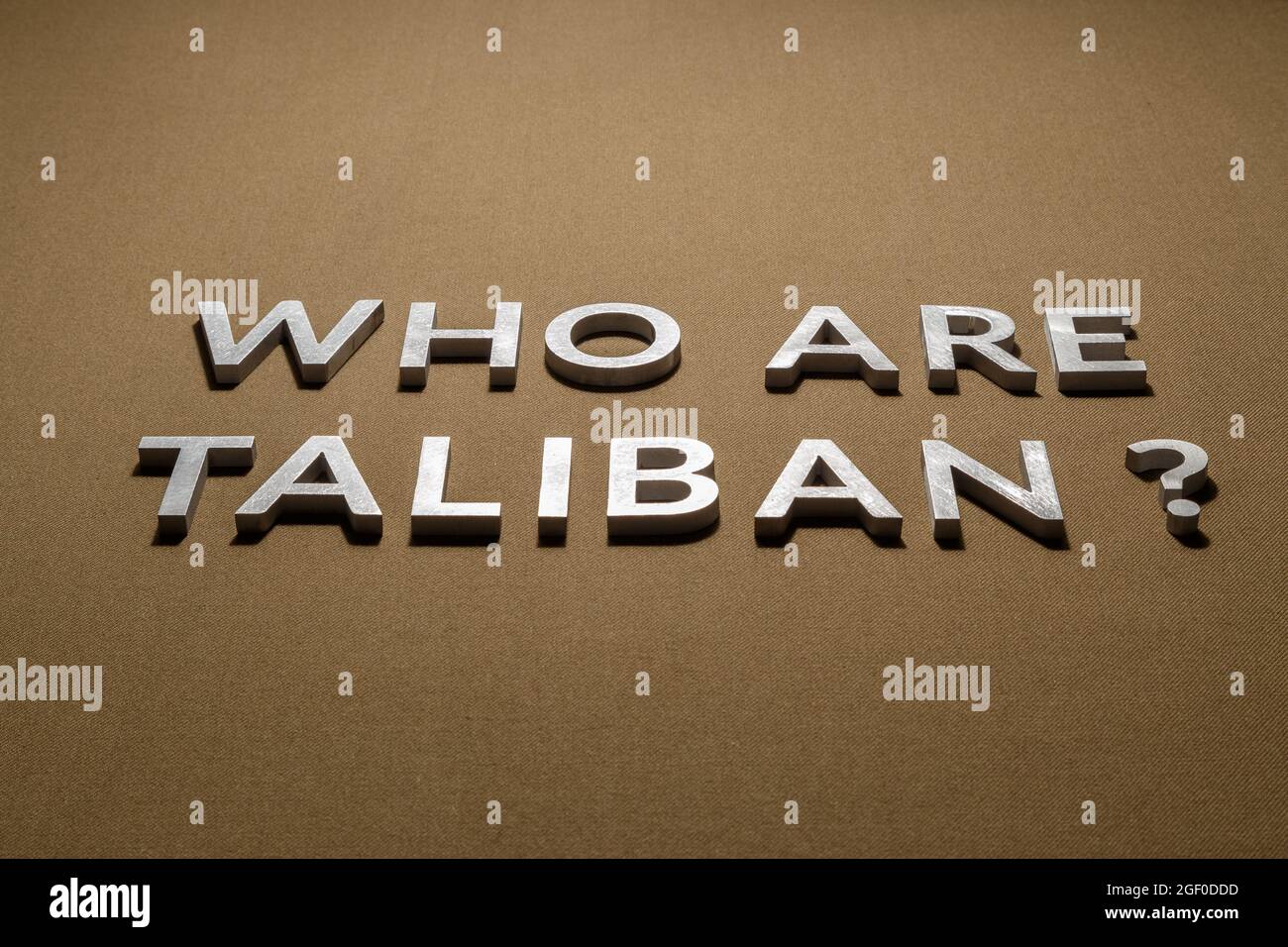 the question who are taliban laid with silver metal letters on rough ...
