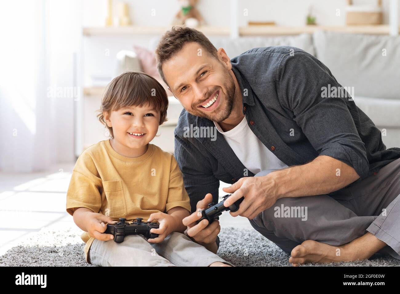 Happy dad enjoying weekend with his little son, playing together video ...