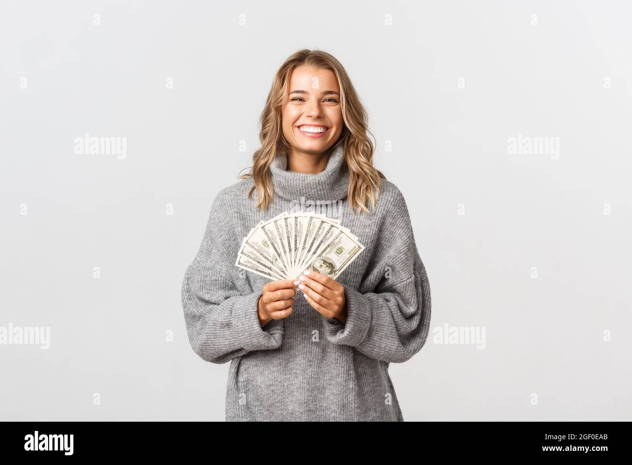 Close-up of happy beautiful woman in grey sweater, holding huge amount ...