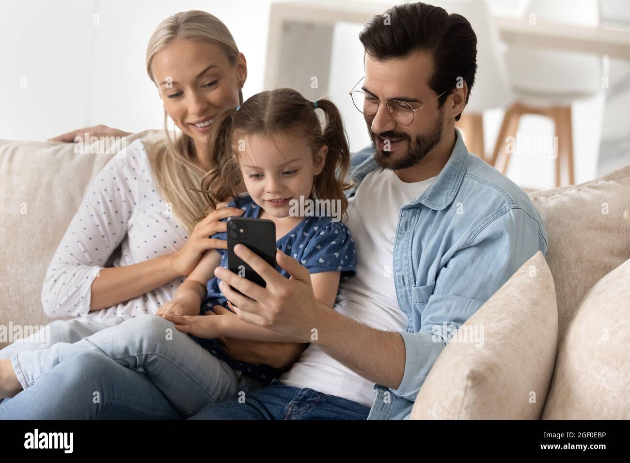Happy parents and sweet gen Z kid using smartphone Stock Photo - Alamy