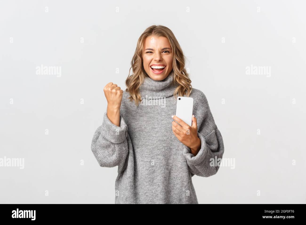 Image of happy winning girl in grey sweater, saying yes and triumphing ...