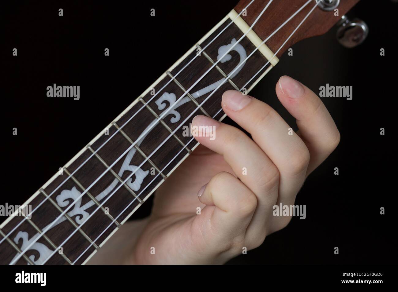 Woman hand playing ukulele on black background Stock Photo - Alamy