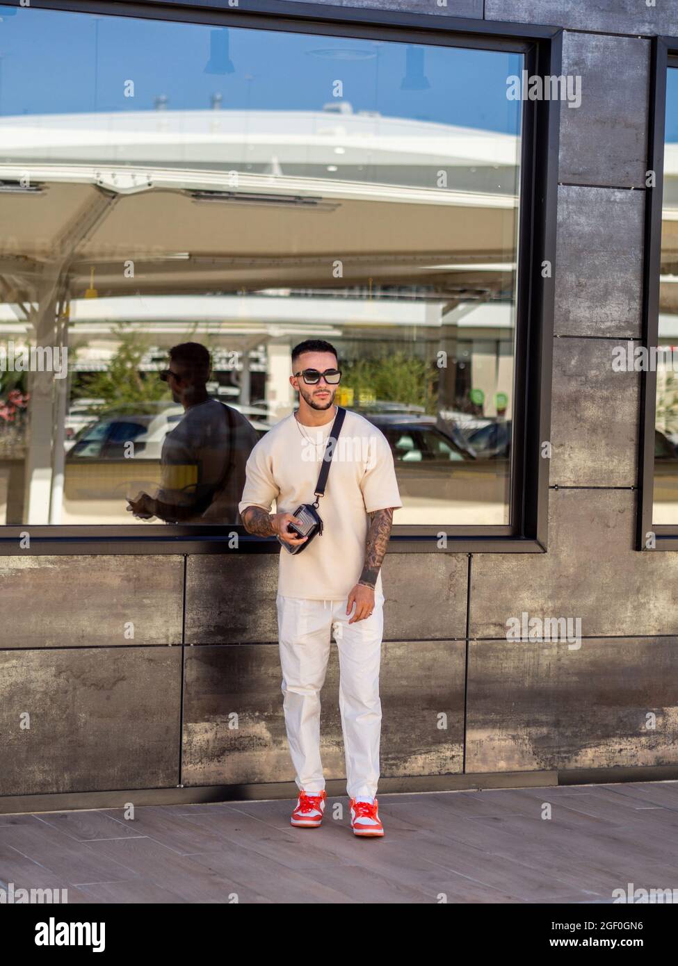 An attractive cool Spanish man with tattoos and sunglasses standing ...