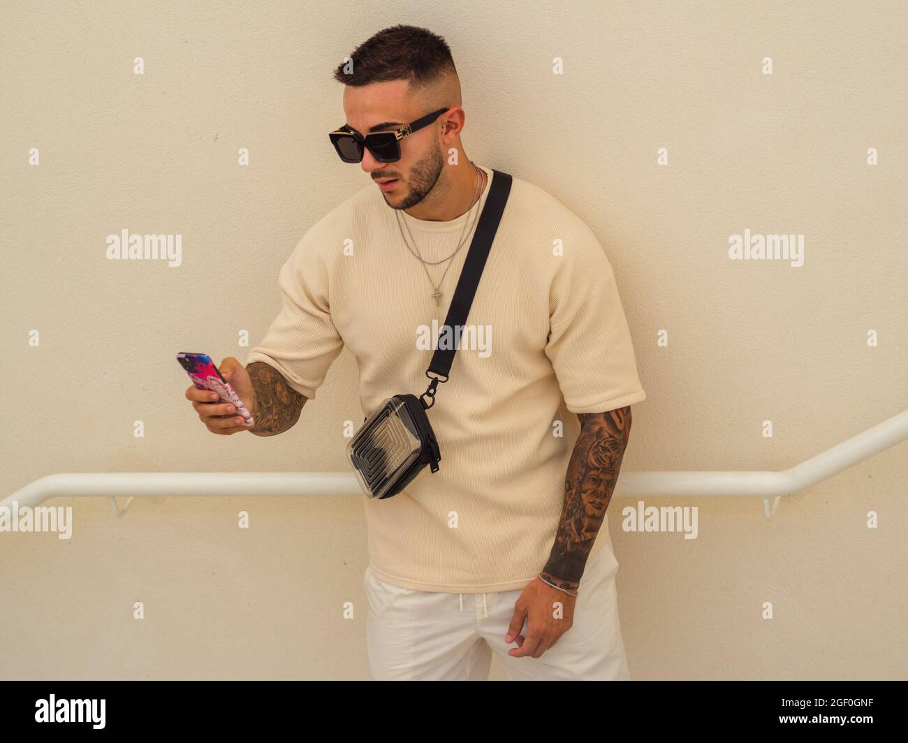 An attractive cool Spanish man with tattoos using his phone while ...