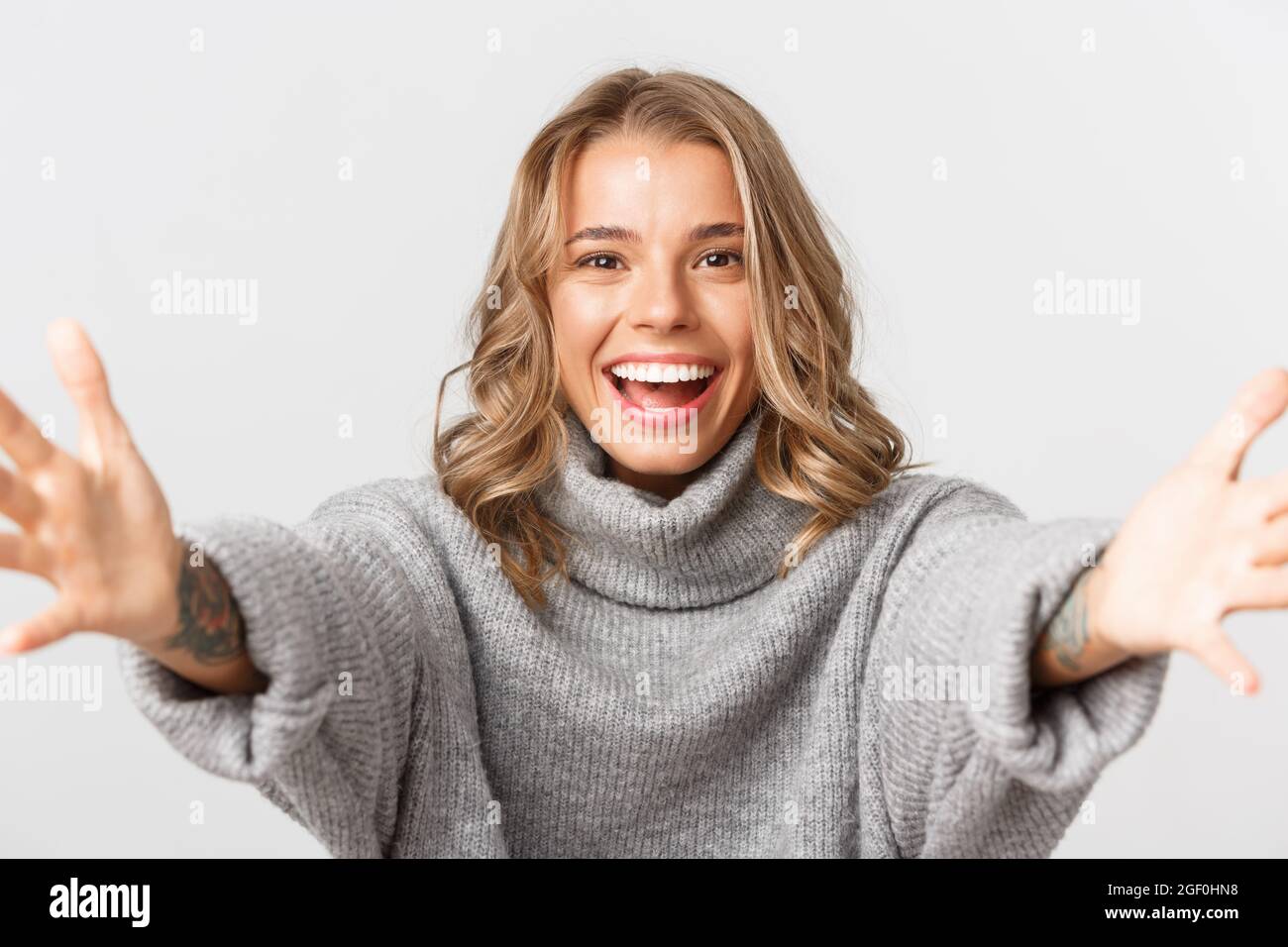 Close-up of happy attractive blond girl smiling, stretching hands ...
