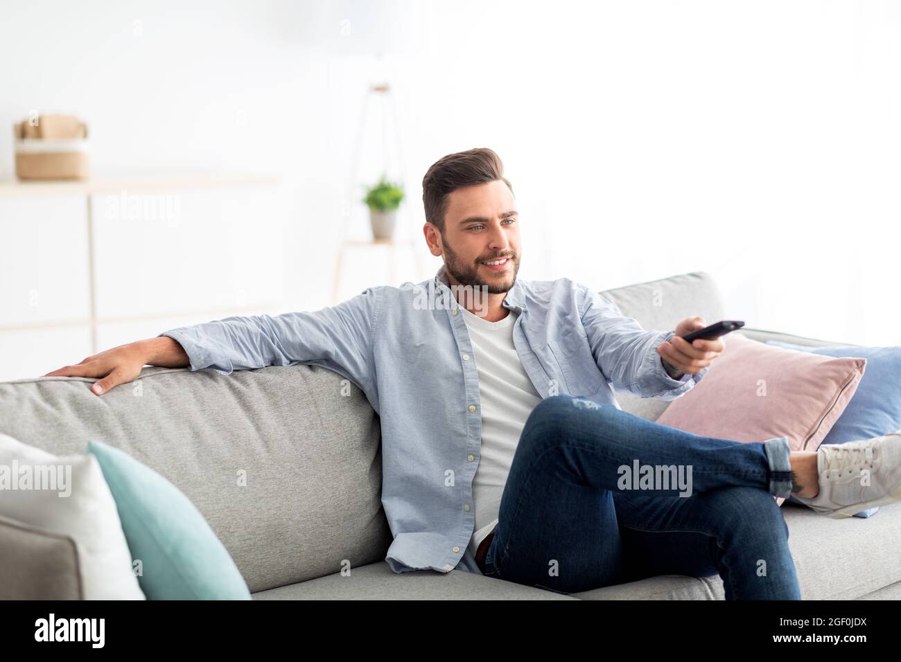 Leisure and entertainment. Happy guy watching TV switching television ...