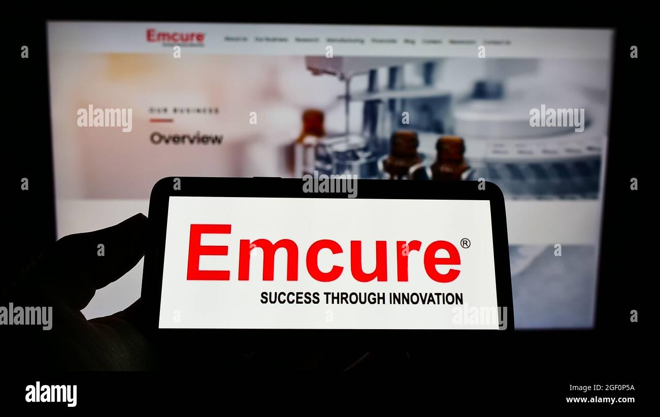 Person holding mobile phone with logo of Indian company Emcure ...