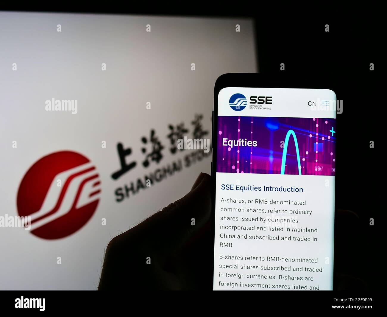 Person holding cellphone with webpage of Chinese Shanghai Stock ...