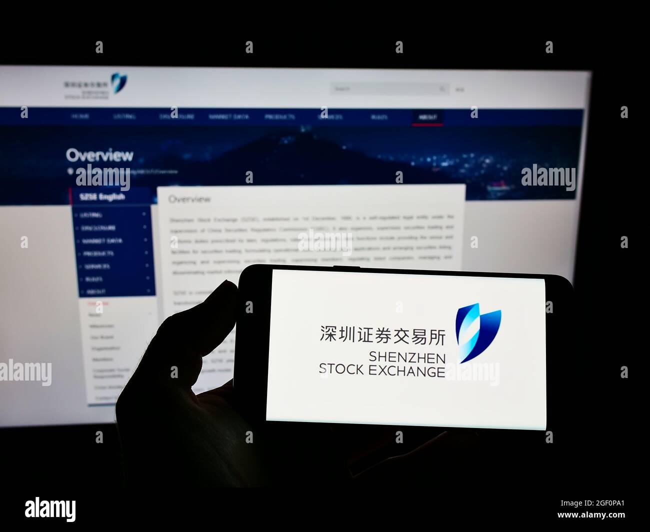 Person holding smartphone with logo of Chinese Shenzhen Stock Exchange ...