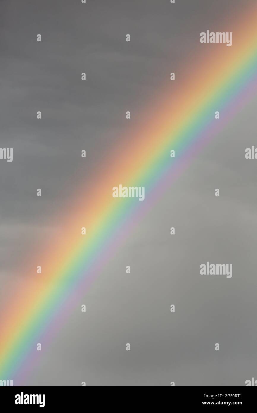 Colourful rainbow in a dark grey stormy sky Stock Photo - Alamy