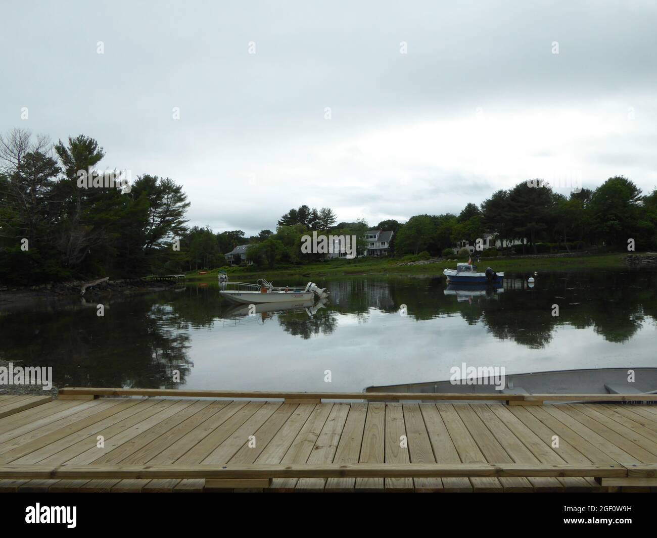 Reflection of empty boats on a lake next to a dock. Village or town ...