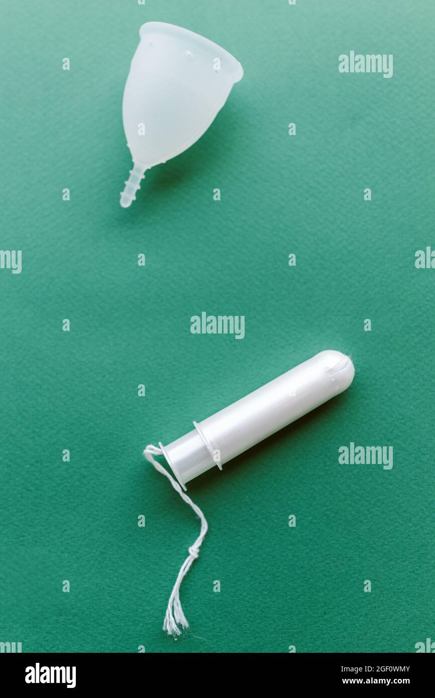 A menstrual cup and a tampon on a green background Stock Photo - Alamy