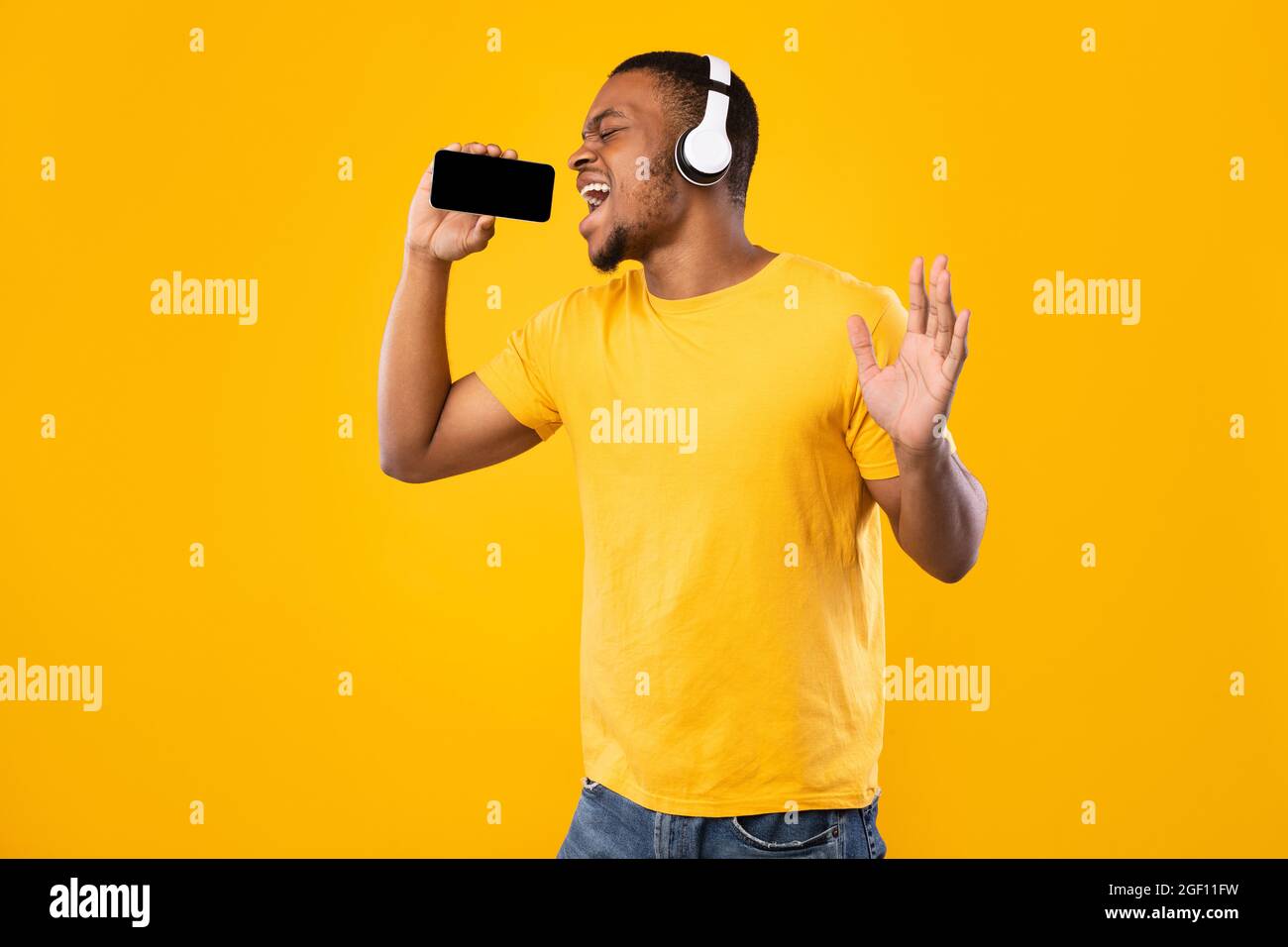 Black Man Singing Holding Smartphone Like Microphone On Yellow ...