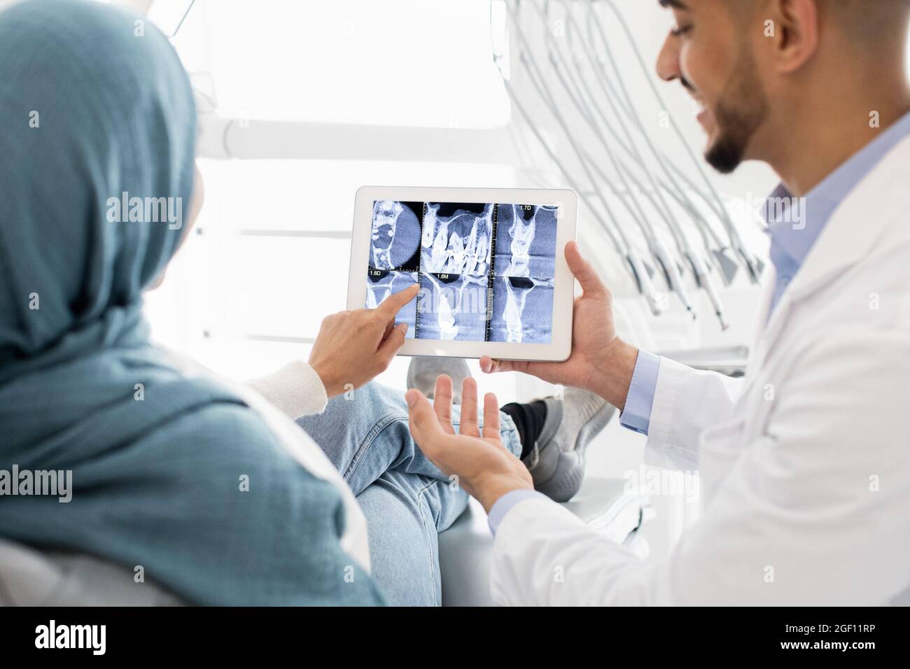 Middle-eastern dentist showing teeth xray on digital tablet to islamic ...