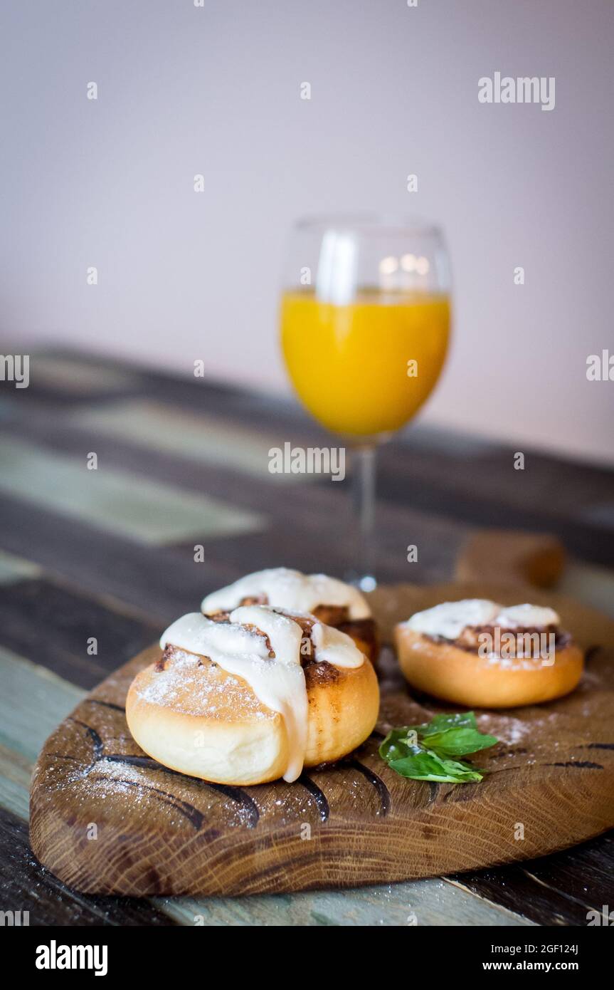 Homemade buns with cinnamon and a glass of juice Stock Photo - Alamy