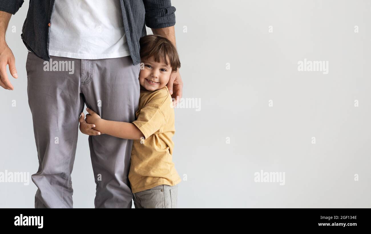 Happy little boy embracing his daddy, smiling to camera, feeling loved ...