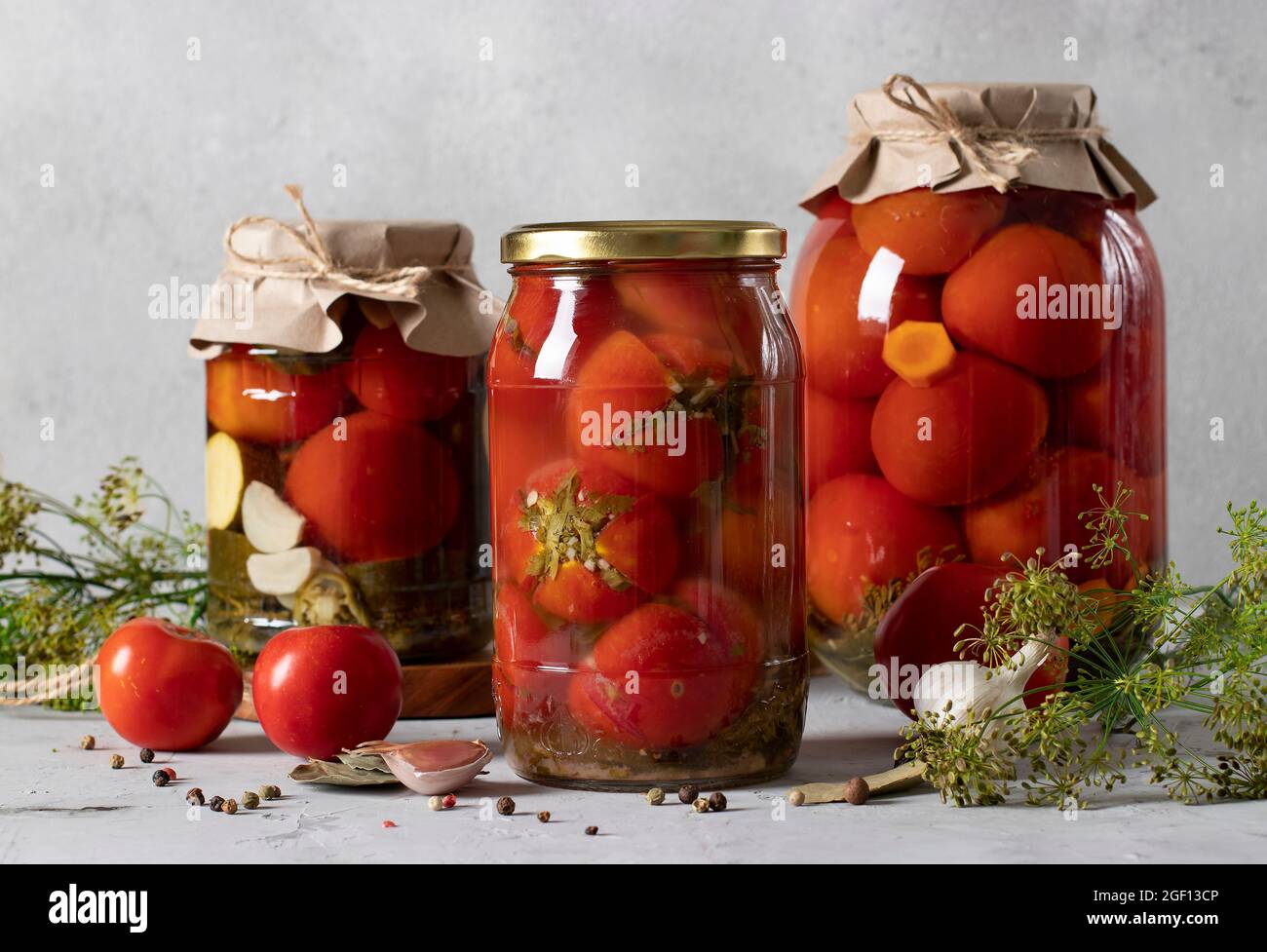 Different marinated tomatoes in jars for the winter on a light gray ...