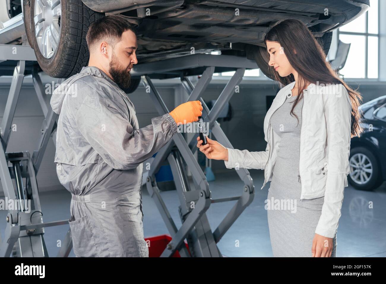 Auto Mechanic giving the car keys to his female customer in workshop at ...