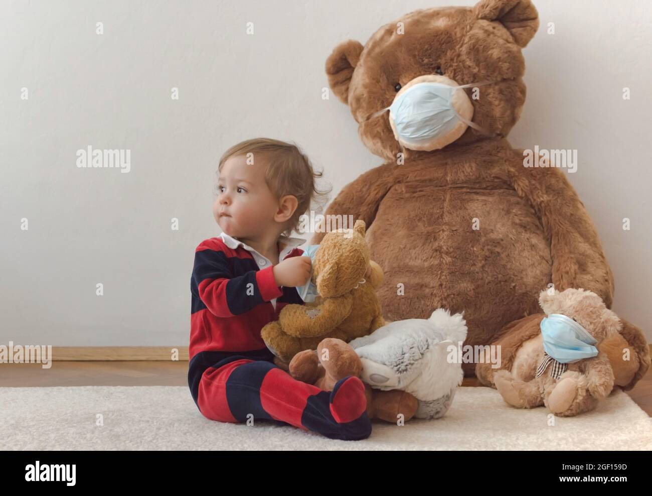 Child playing with his sick teddy bears wearing medical mask against ...