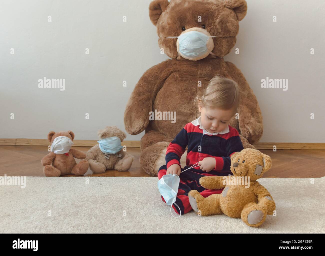 Child playing with his sick teddy bears wearing medical mask against ...