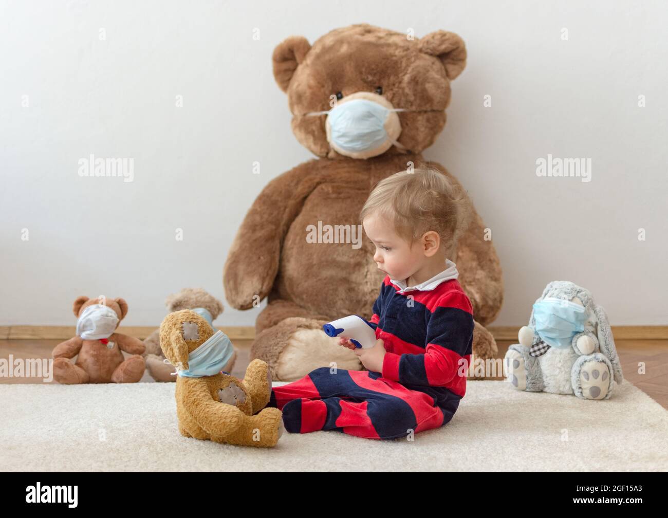 Child playing with his sick teddy bears wearing medical mask against ...