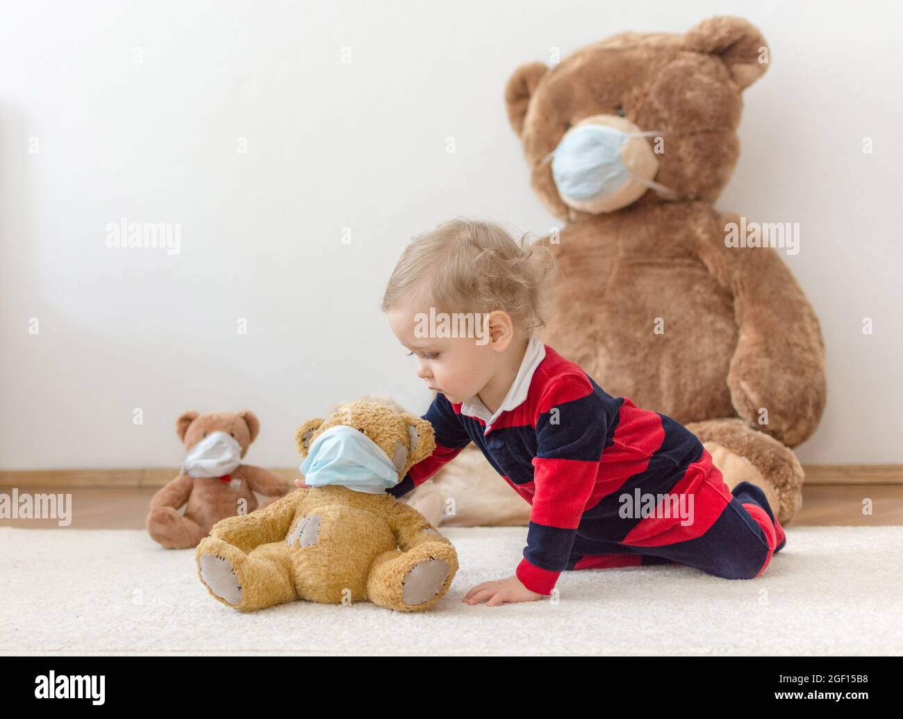Child playing with his sick teddy bears wearing medical mask against ...