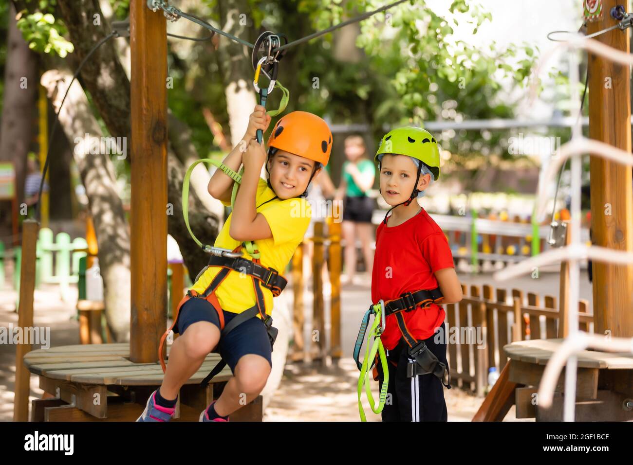 Child in forest adventure park. Kids climb on high rope trail. Agility ...