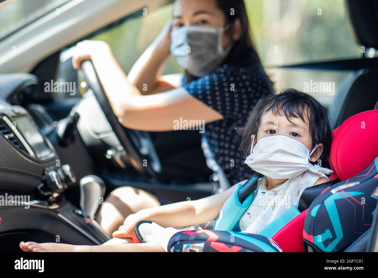A Thai mother driving a car with her daughter on the car seat both ...