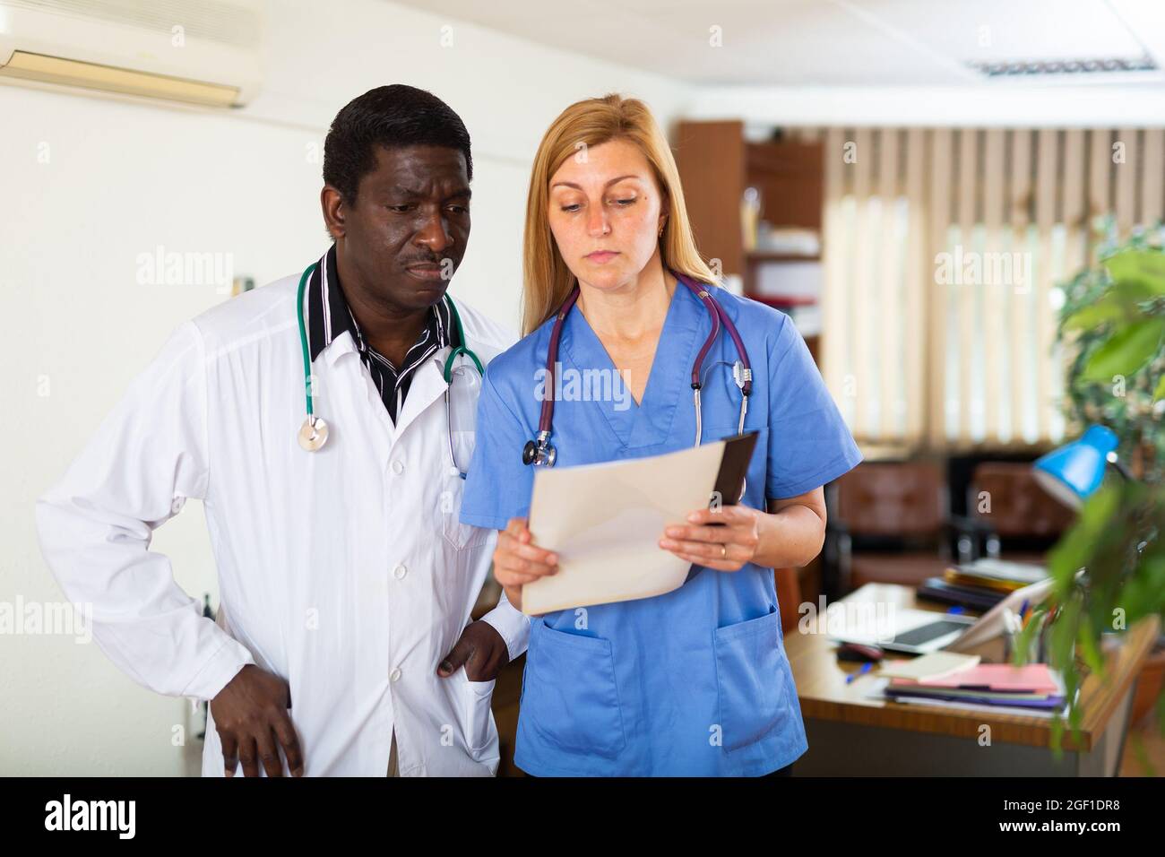 Experienced doctor reviewing medical history with female colleague ...