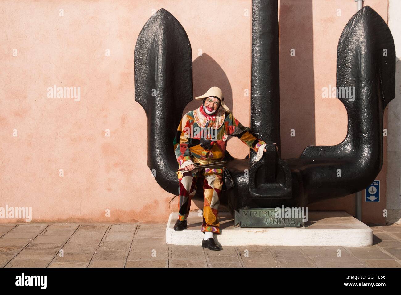 A male wearing a carnival costume sitting on the anchor statue in ...