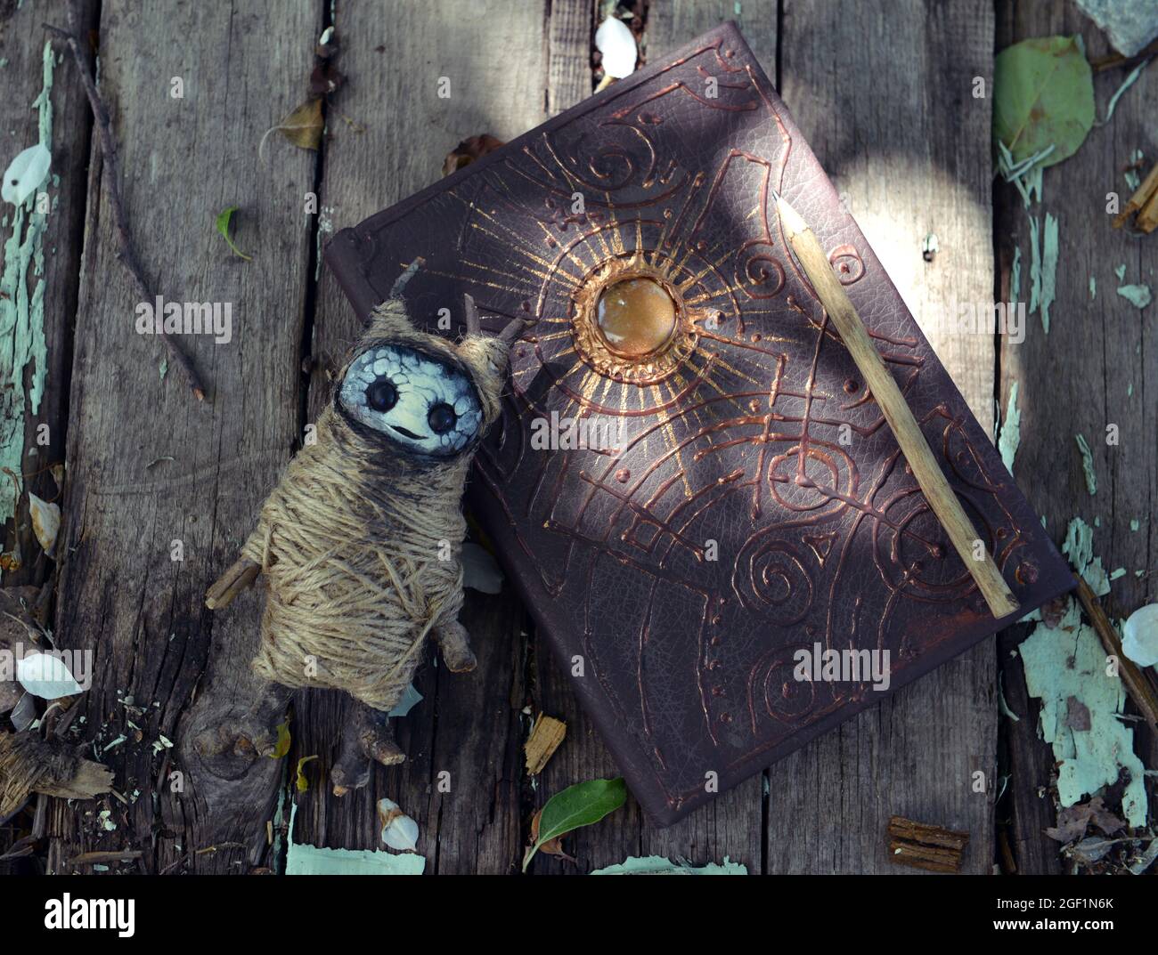 Magic book with decorated cover and voodoo doll on planks in the garden ...