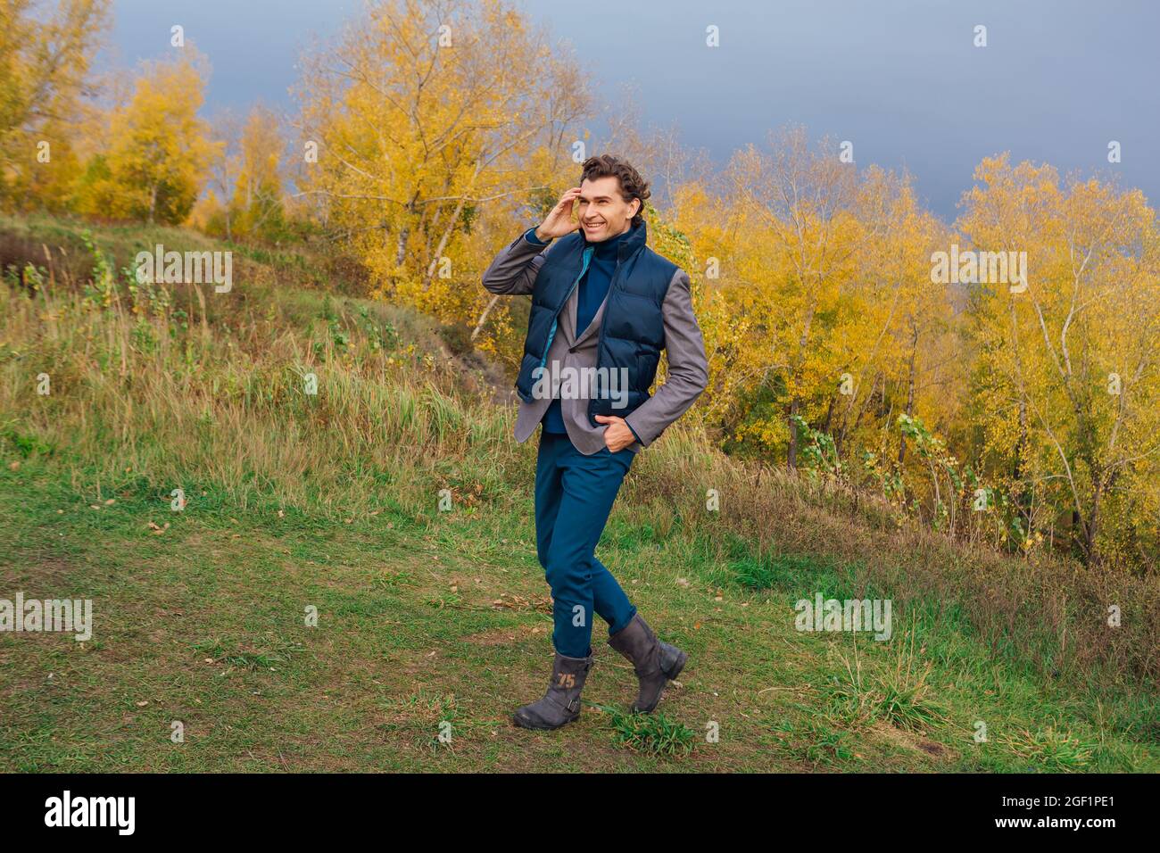 Tall handsome man walking outdoor in yellow autumn forest on the hill ...