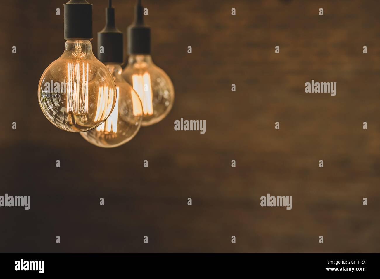 Three lightbulbs on a brown wall background with free space for text ...