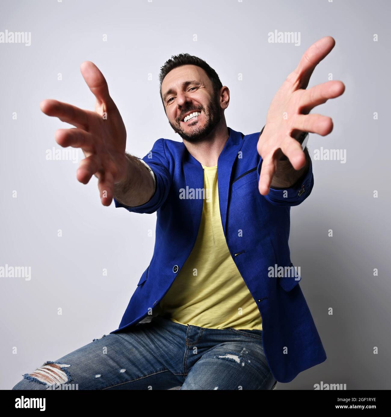 Portrait of friendly smiling adult man in casual clothing sitting on ...