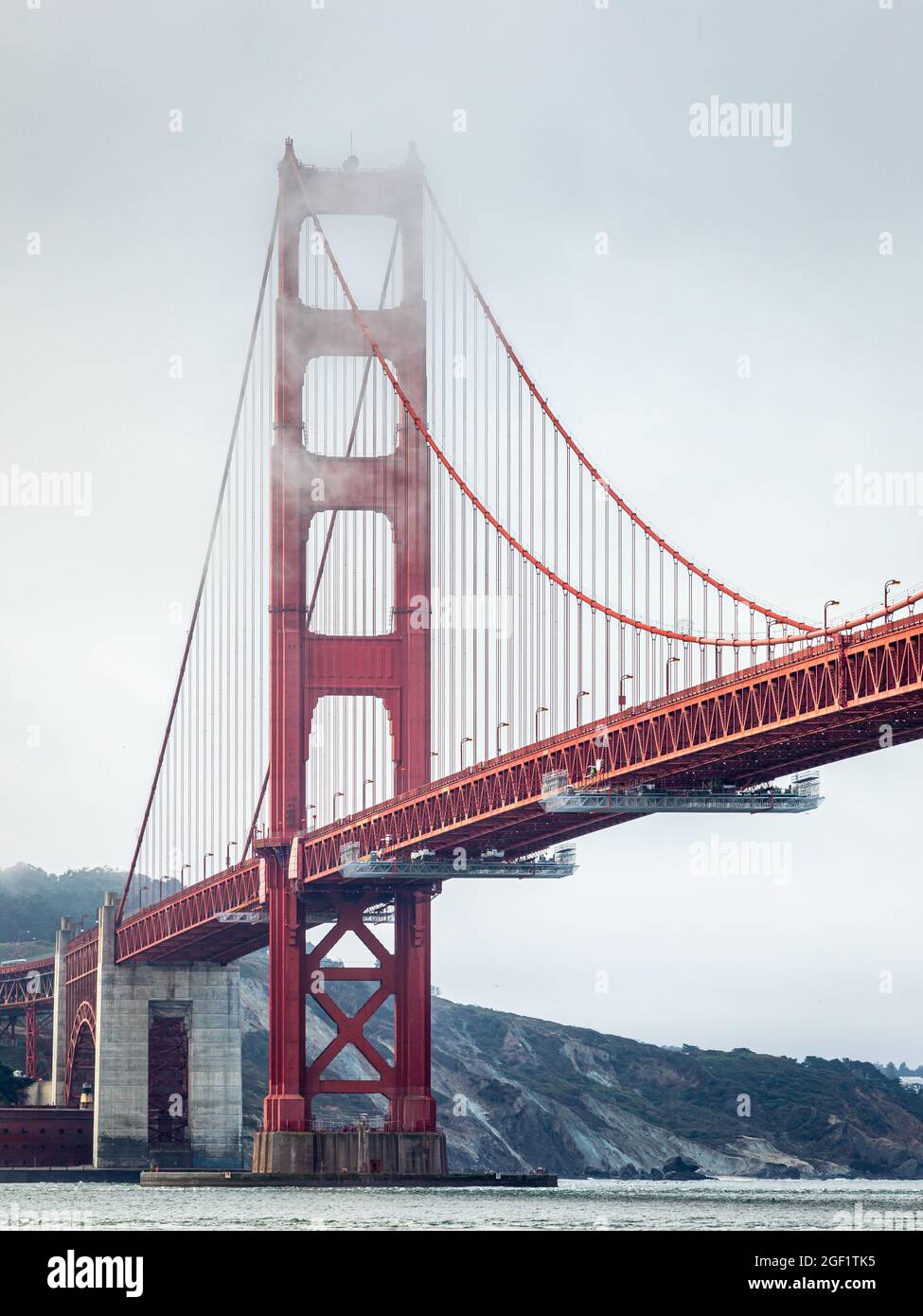 Vertical scene of the Golden Gate bridge covered by fog at overcast ...