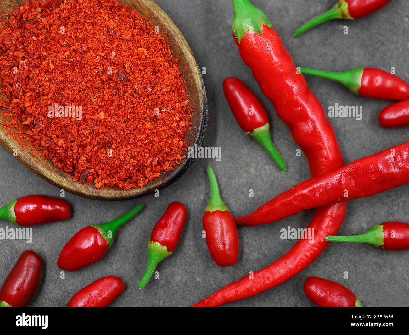 dried chili flakes with various red hot chili peppers on dark ...