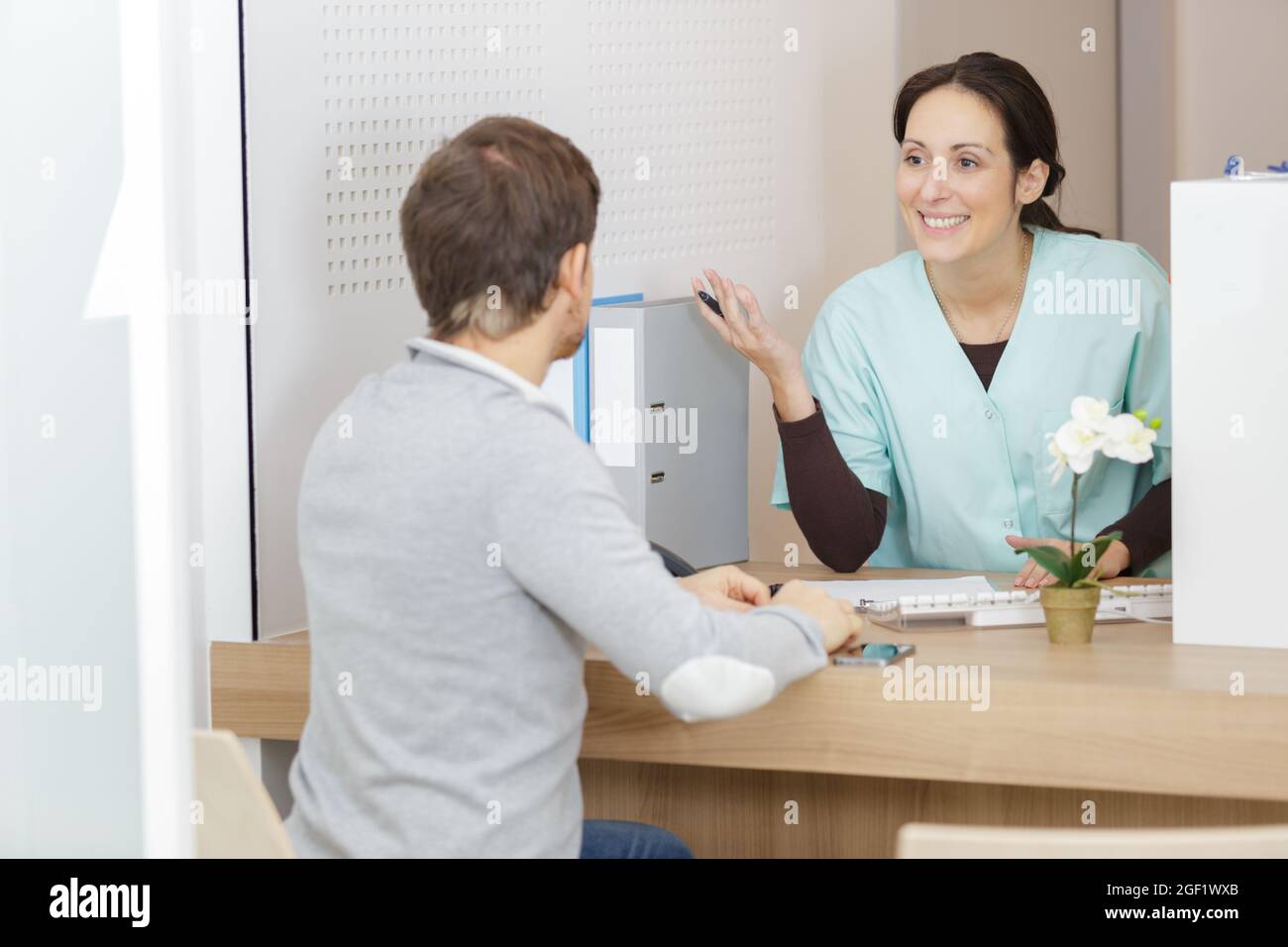 female receptionist with male patient in hospital Stock Photo - Alamy