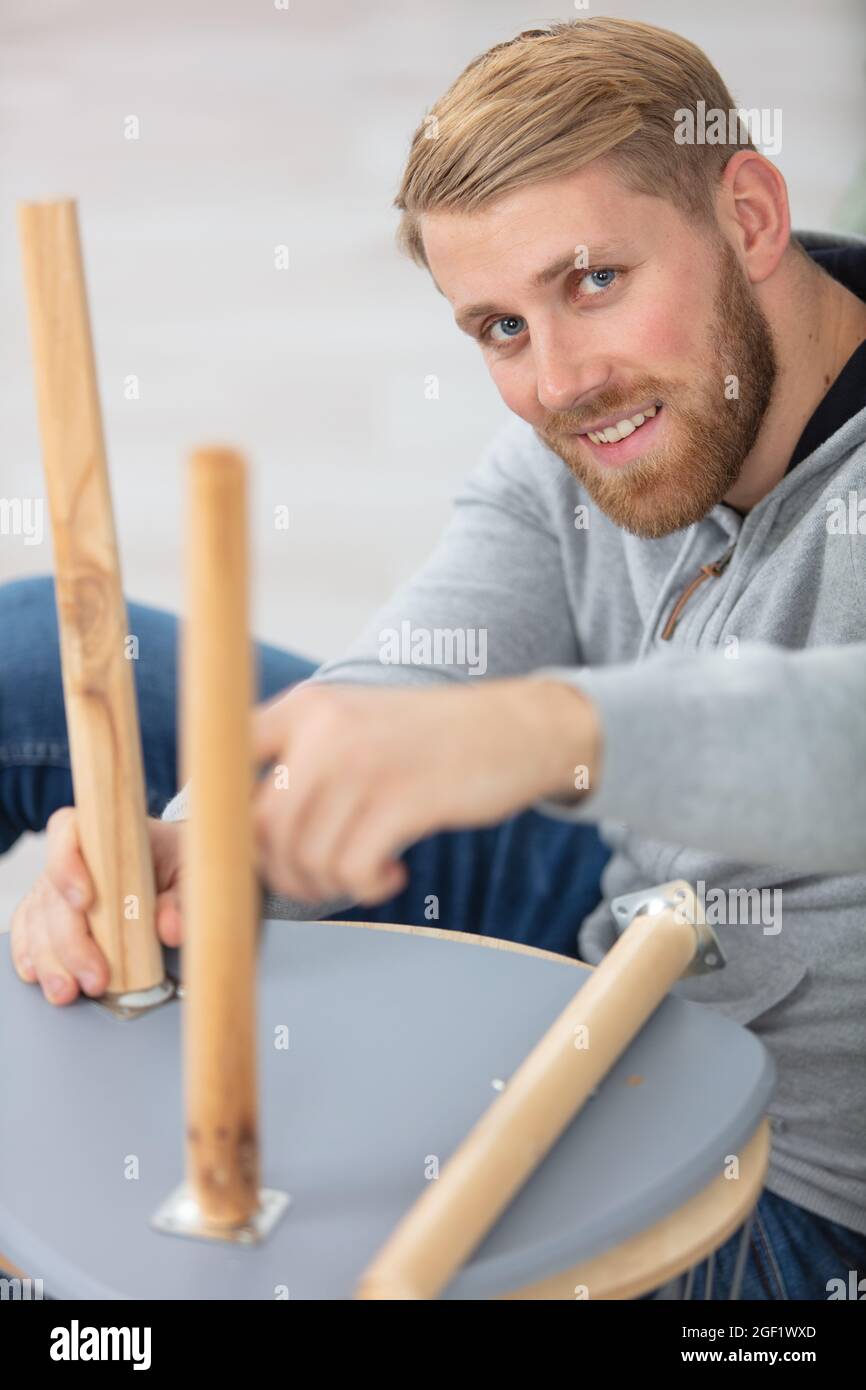 man fixing legs on to a chair Stock Photo - Alamy