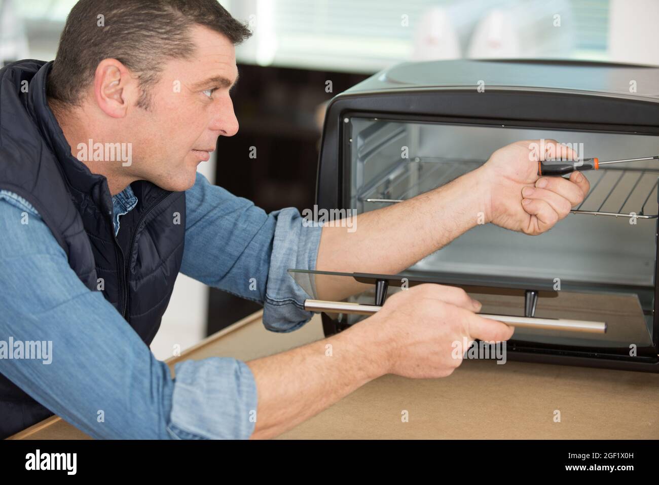 concentrated man fixing an oven with screw driver Stock Photo - Alamy